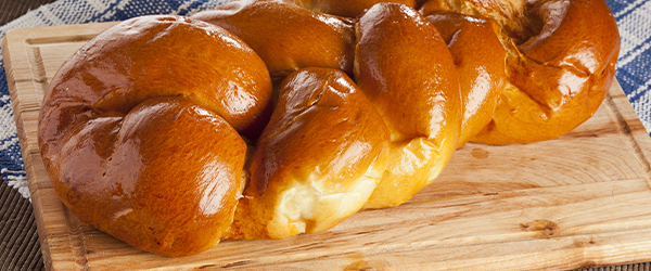 A buttered and knotted bread sits on a wooden board.